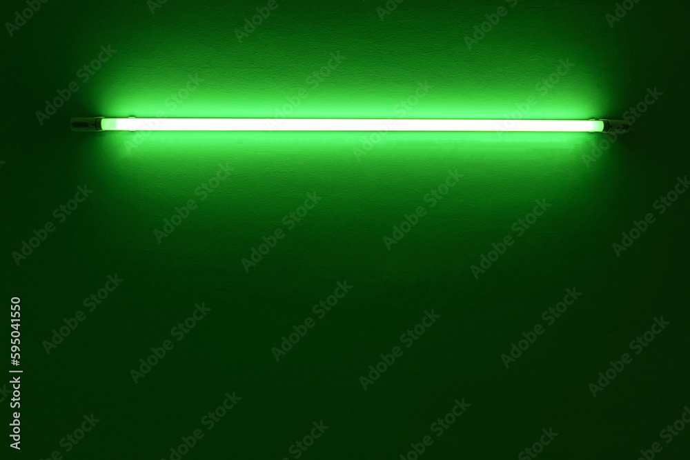 Foto de green neon light bulb on white wall. do Stock | Adobe Stock
