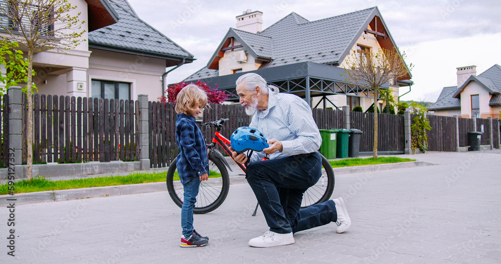 Caucasian grandfather teaching small cute grandson riding a bike ...