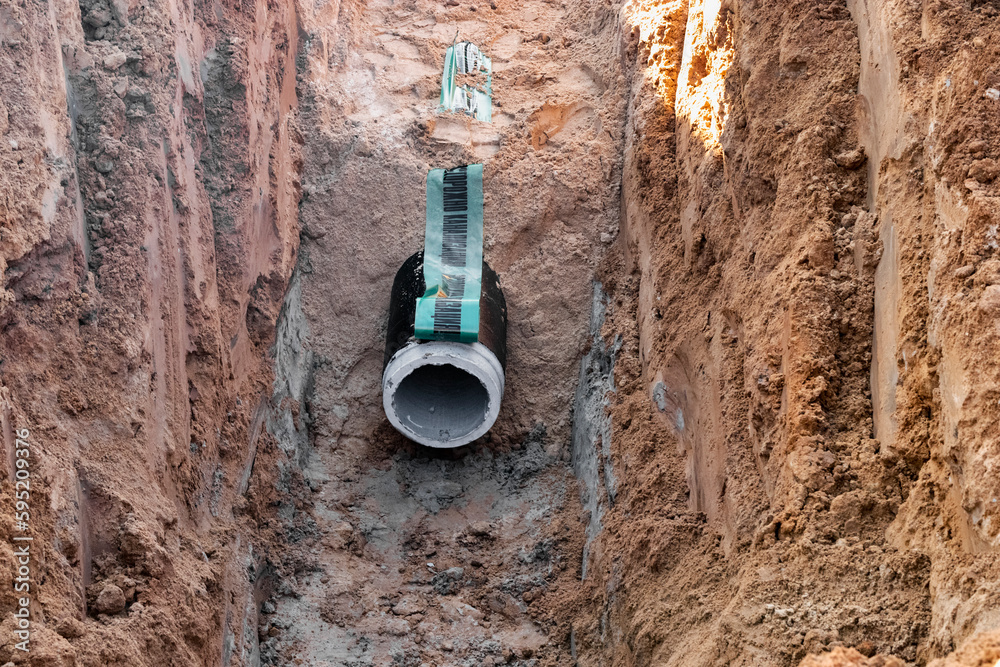 Laying a reinforced concrete sewer pipe in a trench. Reconstruction of ...