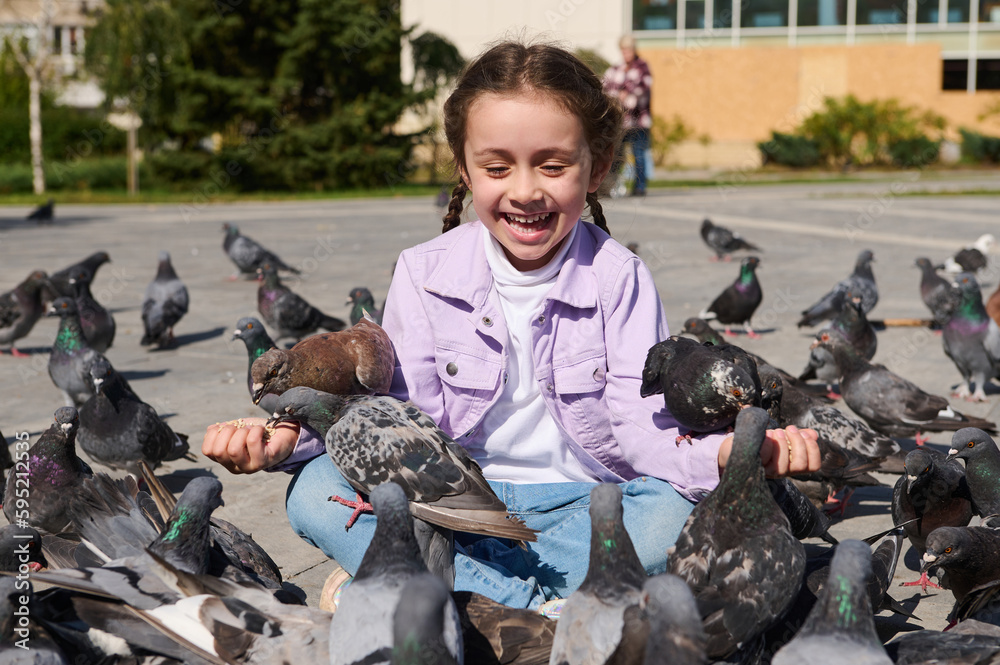Adorable little Caucasian child girl sitting in lotus pose, feeding ...