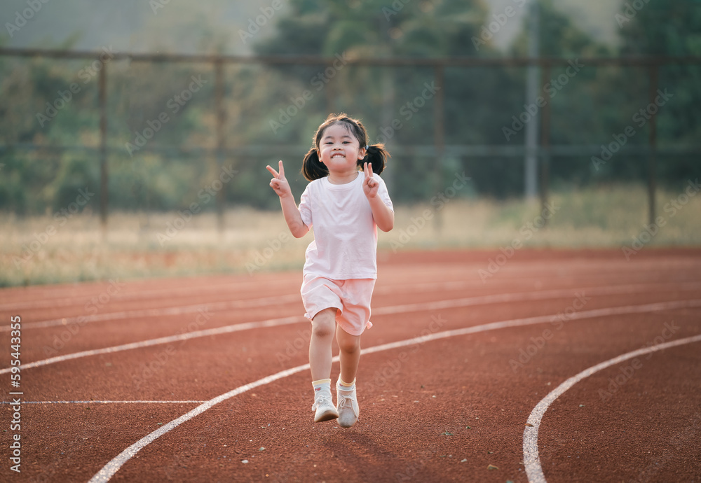 Baby asian girl run jogging at running track, running field at stadium. little girl running at ...