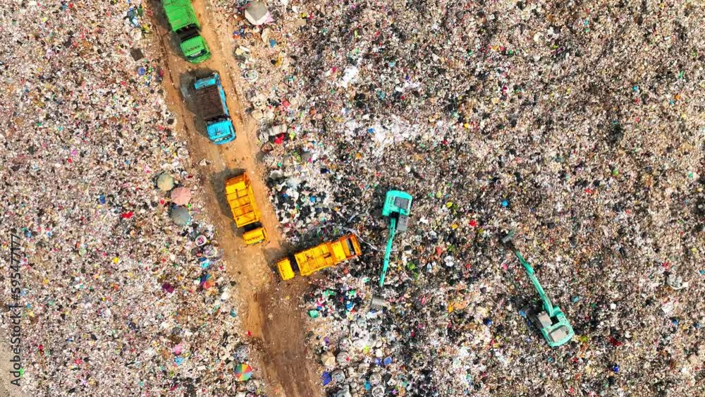 Garbage trucks transport waste to landfills and excavators spread and ...