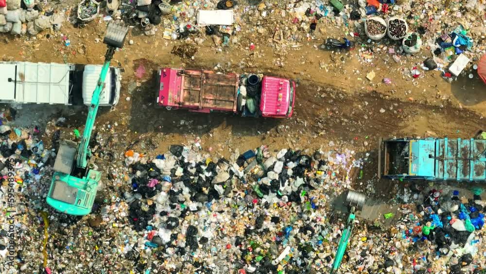 Garbage piles are cleared by workers using excavators to scoop waste ...