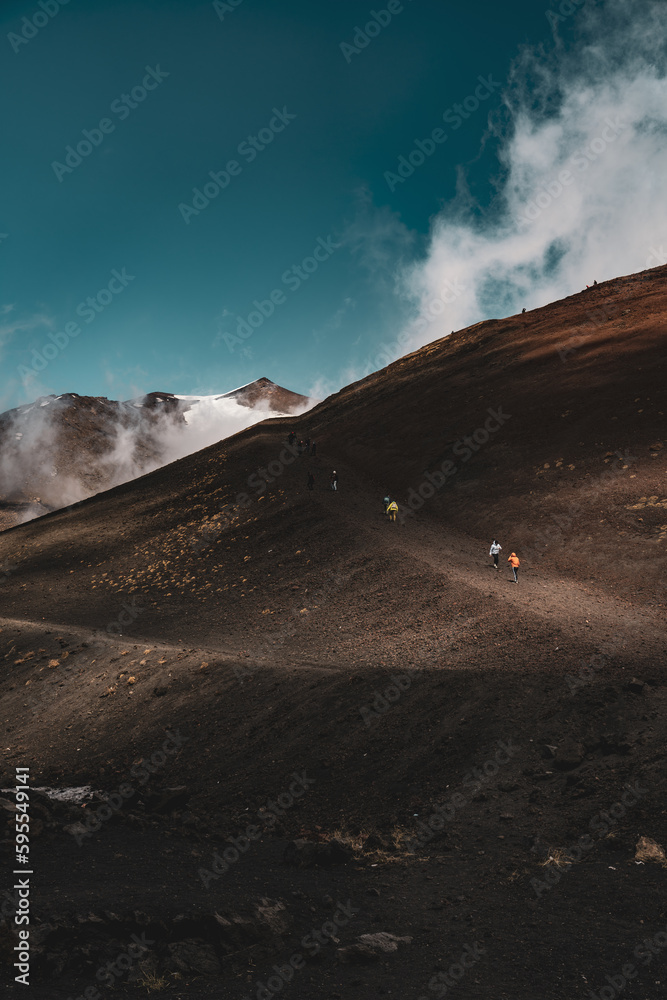 Tourists walk on mountain paths of Etna volcano. Groups of hikers ...