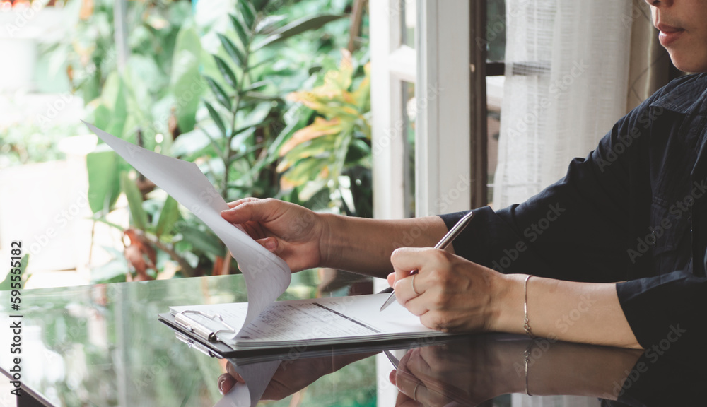 Businesswoman's hand with pen completing personal information on a form ...