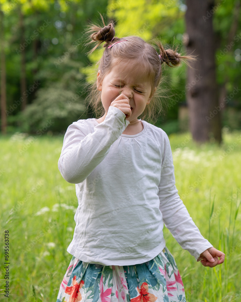 Charming beautiful little girl walks in the park. She tightly closed ...
