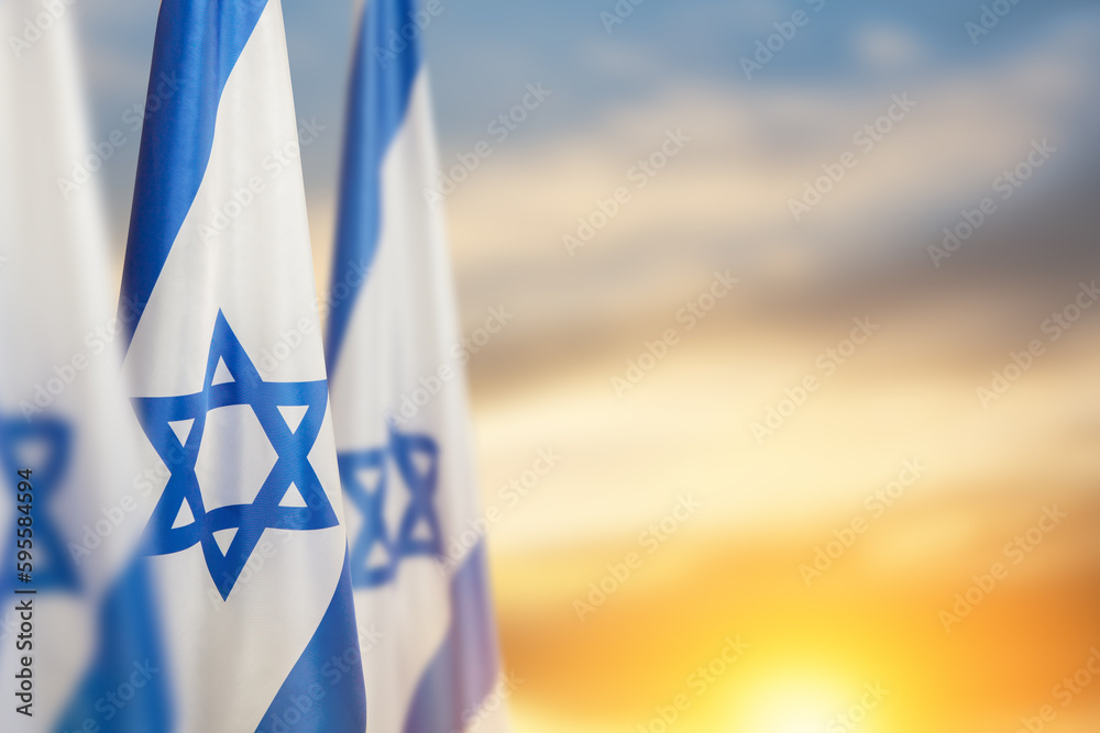 Israel flags with a star of David over cloudy sky background on sunset ...