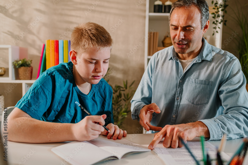 Father explaining his son how to resolve the problem with his homework ...