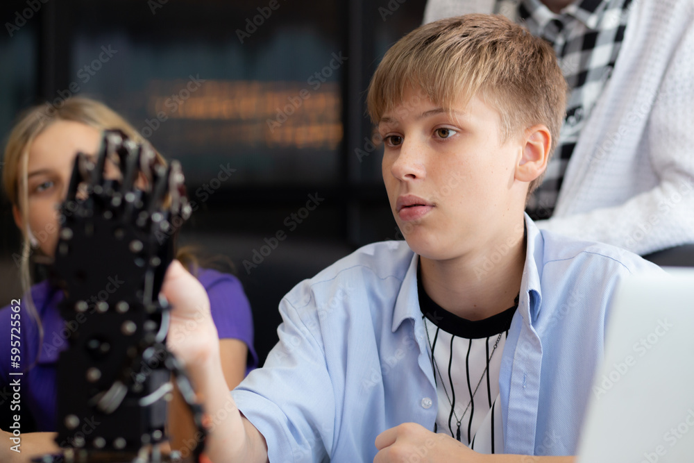 Caucasian two teenager students learning robotic arm in classroom ...