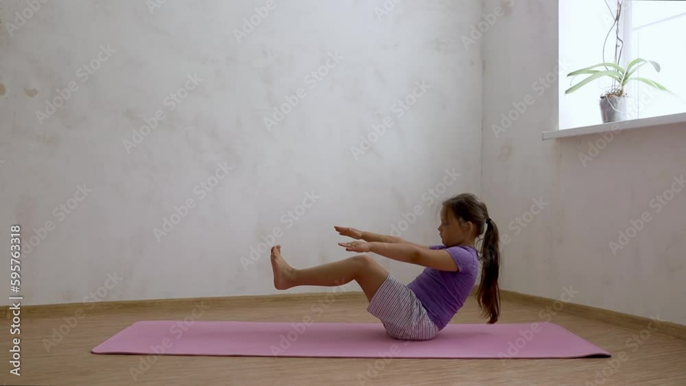School age girl sitting keep raised bent legs on exercise mat in empty ...