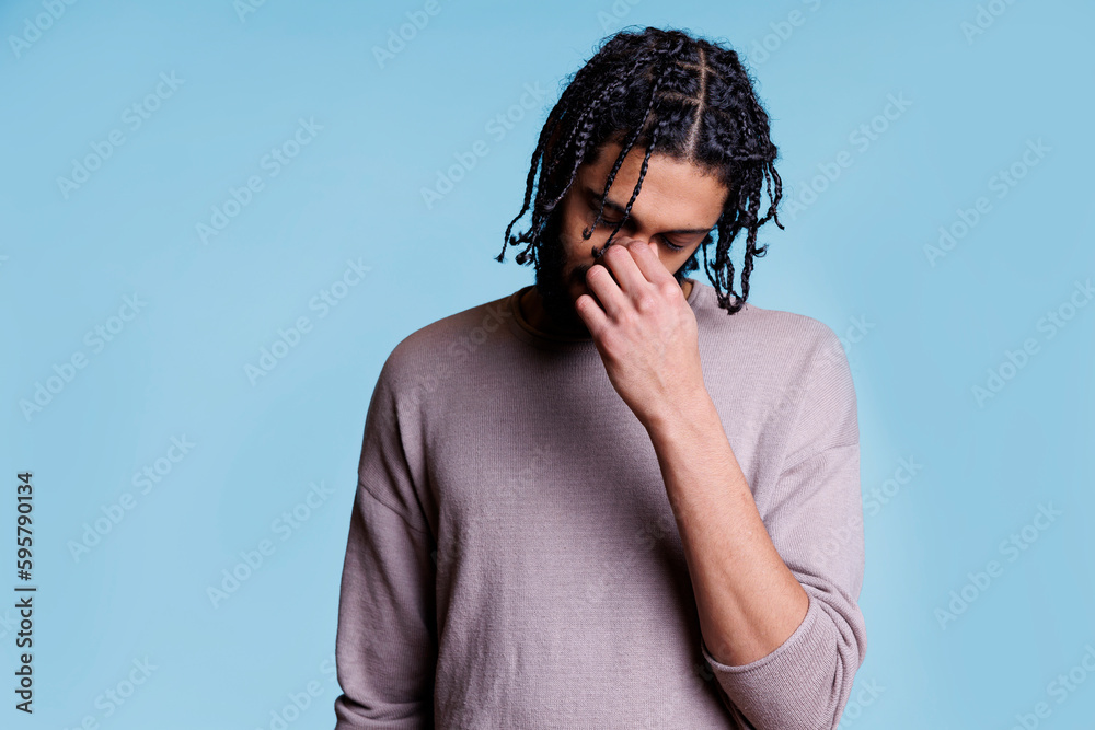 Tired arab man with closed eyes holding nose while suffering from sinus ...