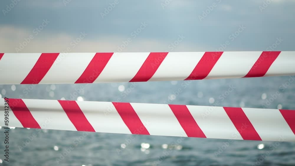 Red white warning tape barrier ribbon swinging in the wind across ...