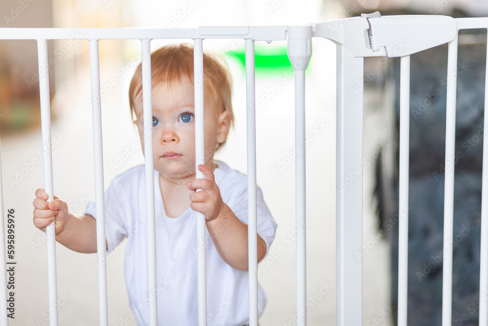 Sad little girl standing at locked baby safety gate and fence Stock ...