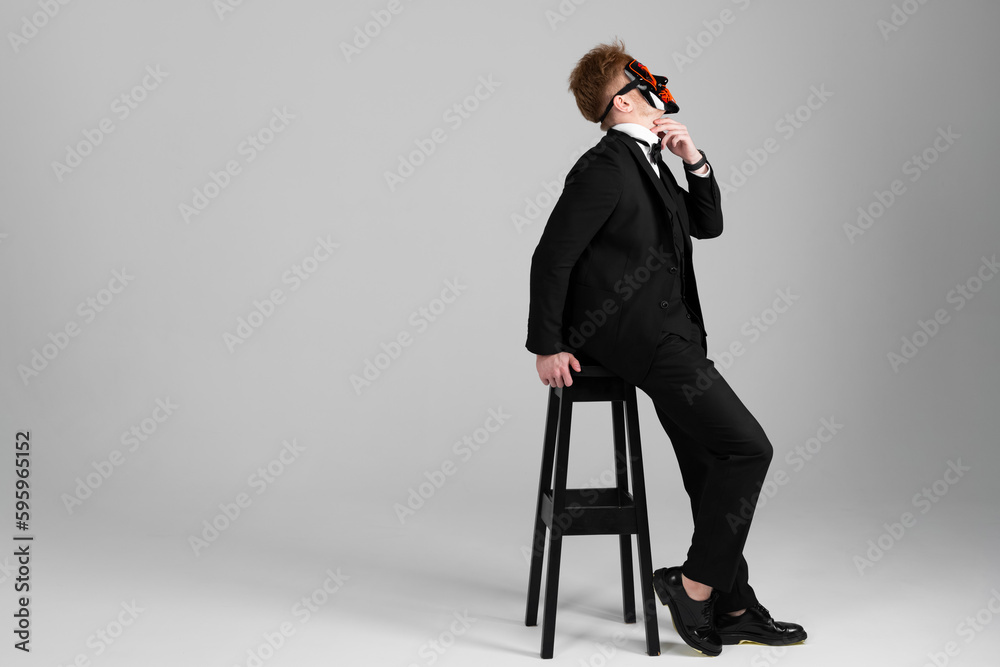 Stylish young man in a sharp black formal suit wearing a bright face ...