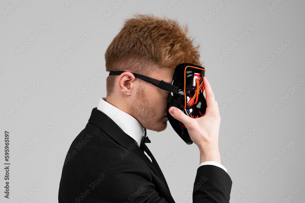 Stylish young man in a sharp black formal suit wearing a bright face ...