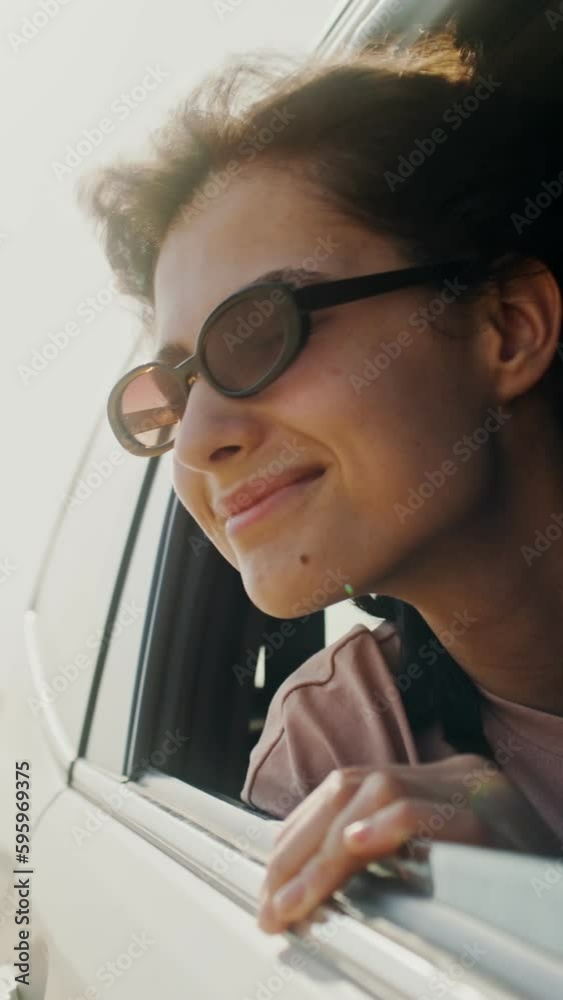 A young beautiful woman with glasses is smiling looking out of the ...