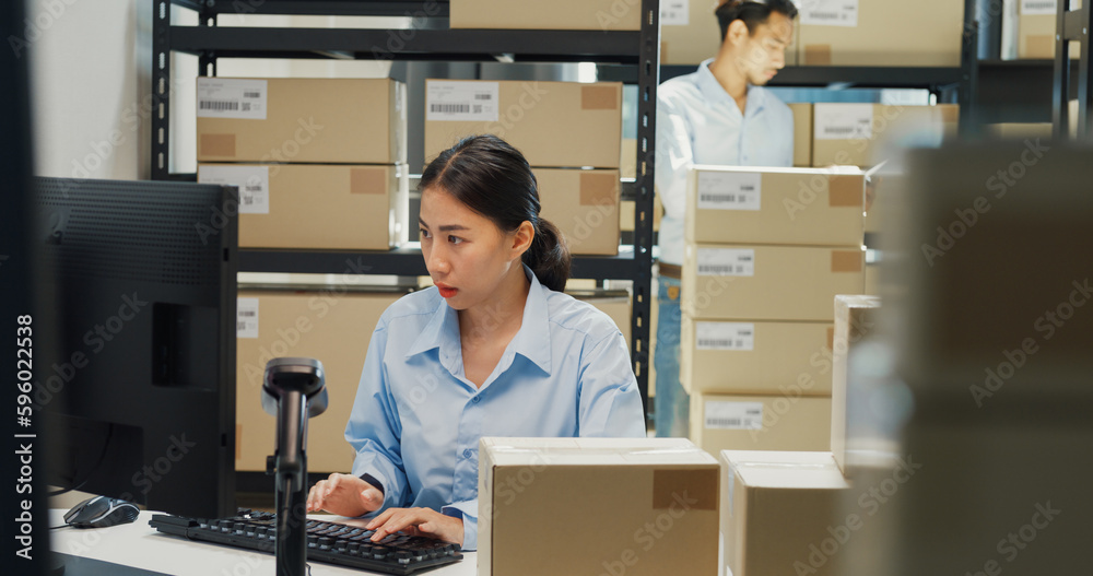 Happy Asian girl and man partner wear formal shirt sit front desk computer use barcode machine ...