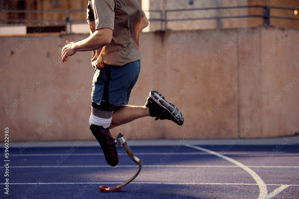 Fit man with a prosthetic blade running on an outdoor track foto de ...
