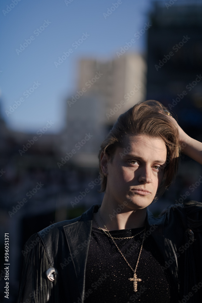 Wearing a cross necklace, a young gender-fluid person expresses their ...