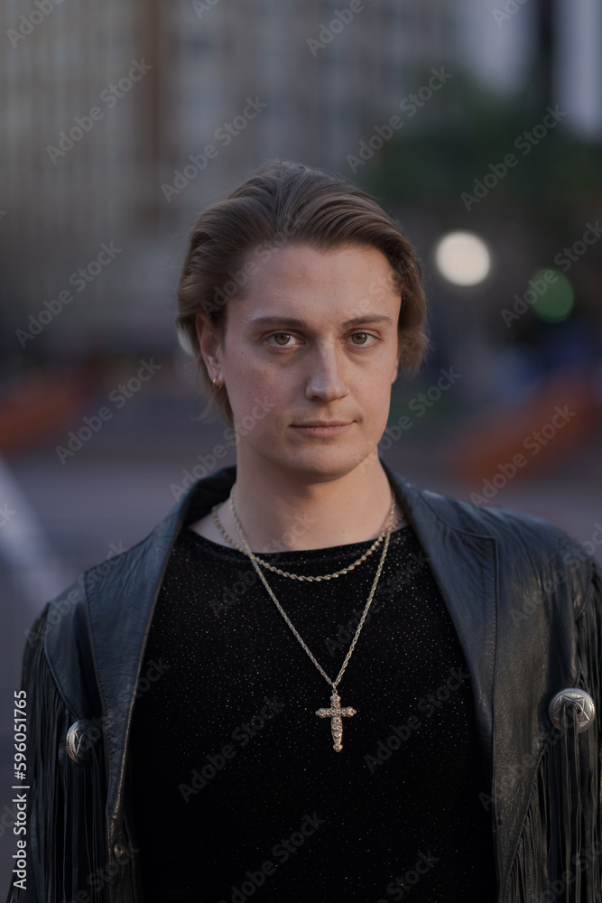 Wearing a cross necklace, a young gender-fluid person expresses their ...