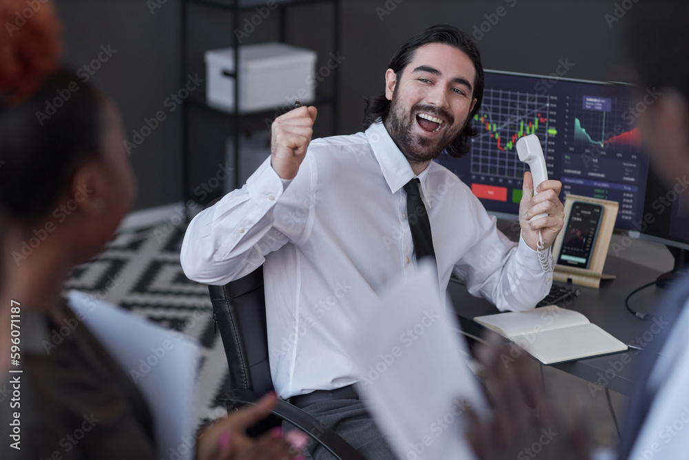 Young successful broker selling the stocks to customer by the phone ...
