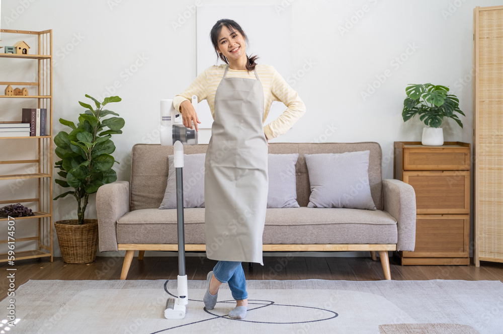 asian lady doing house chores in apron. young housewife using vacuum ...