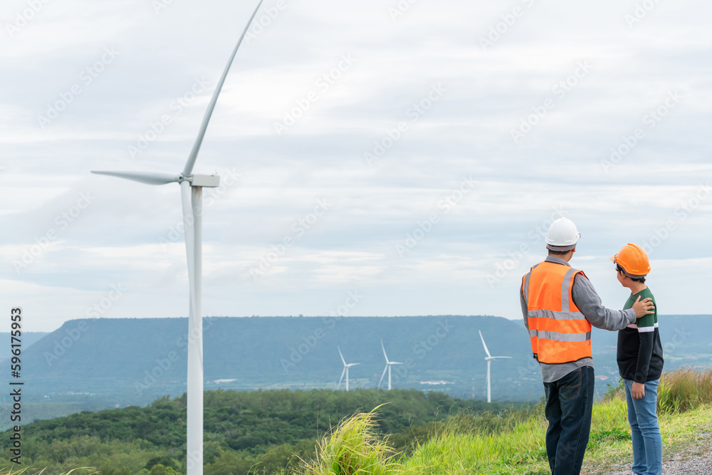 Engineer with his son on a wind farm atop a hill or mountain in the ...