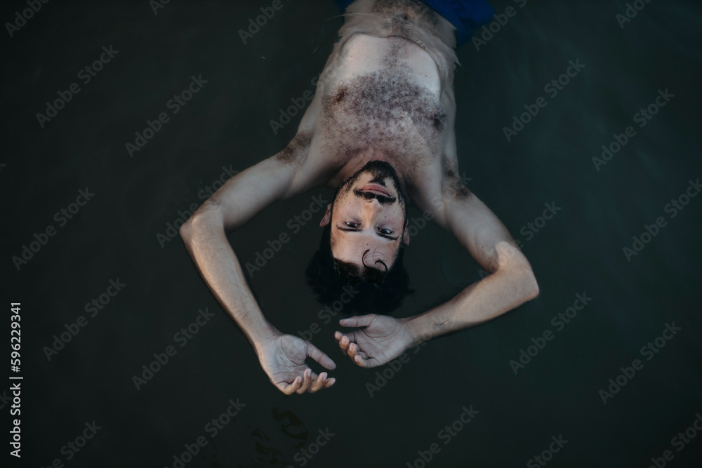 Shirtless man with arms raised floating in sea Stock Photo | Adobe Stock
