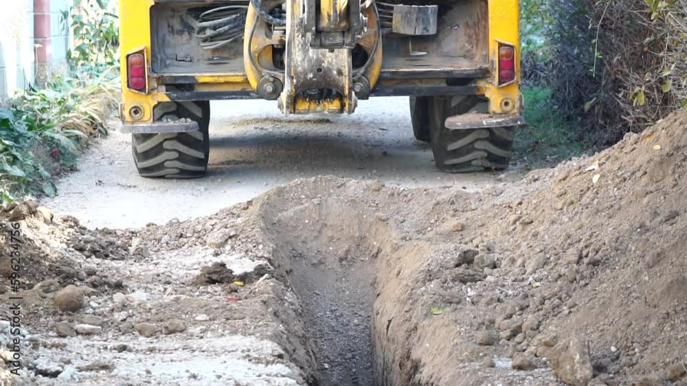 Excavator digs a trench to lay pipes. Close up of an excavator digging ...