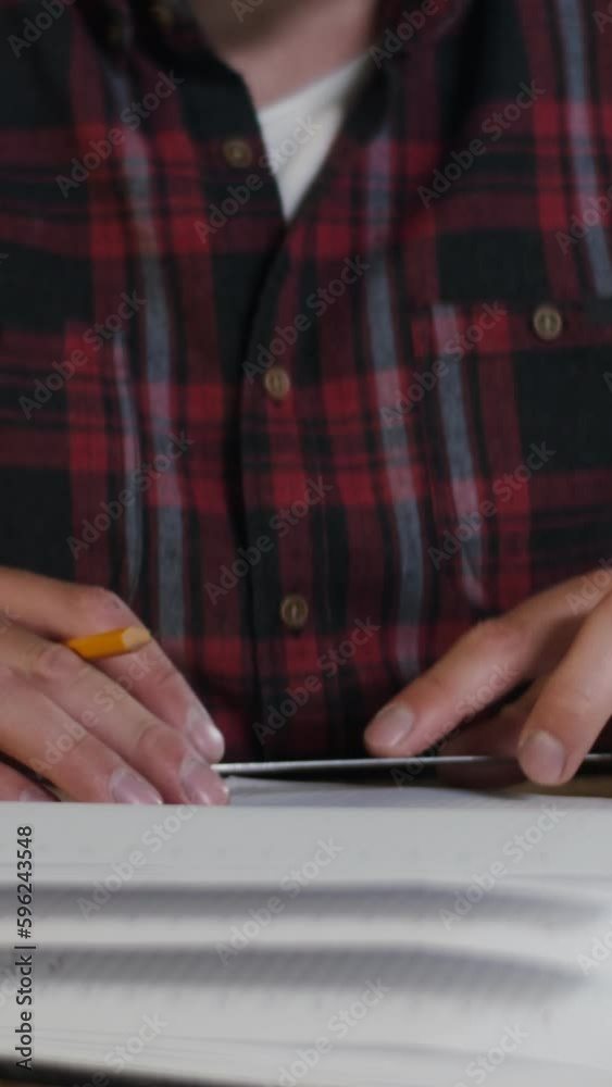 man in a plaid shirt, makes a pencil drawing in a notebook using a ...