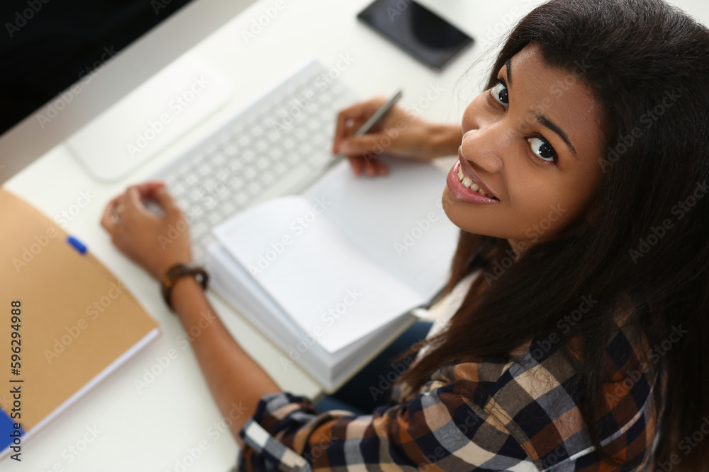 Foto de Smiling African American woman takes notes and writes in ...