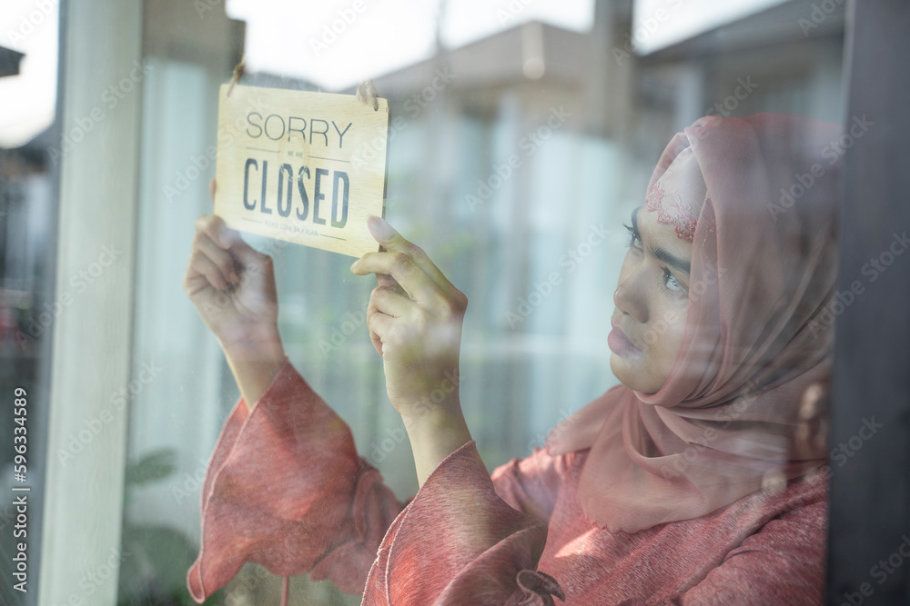 Beautiful Islamic woman hanging 'sorry we are closed' sign on glass ...
