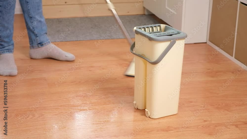 Vidéo Stock A man squeezes a mop into a bucket and washes the floor ...