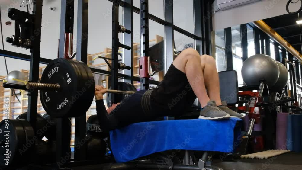 Vidéo Stock Barbell bench press. A young athlete on a simulator in a ...