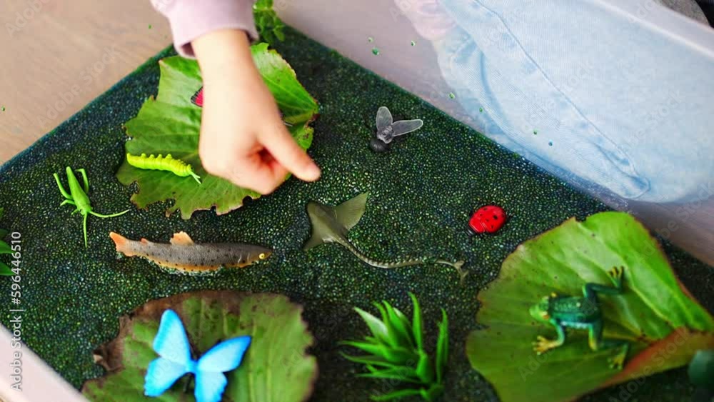 Little girl playing in handmade swamp of green-dyed chia seeds with ...