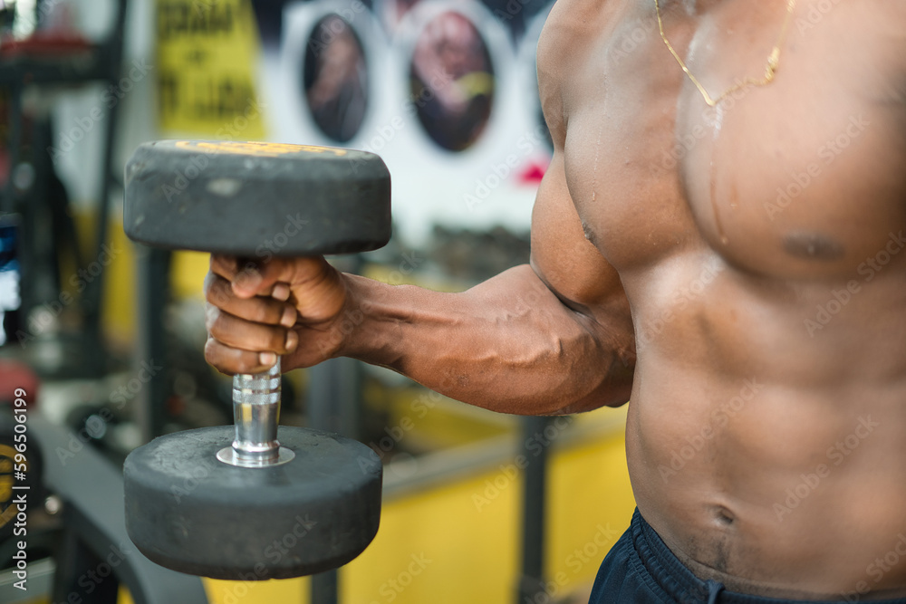 A strong black man is inside a gym, pushing himself to the limit with ...