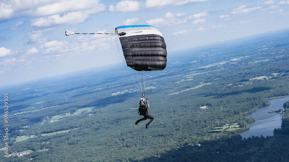 Skydiver flying parachute canopy over lake and fields with clouds Stock ...