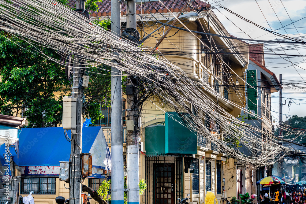 Thick mass of power cables,hanging above and along a main street in Intramuros,the old Spanish ...