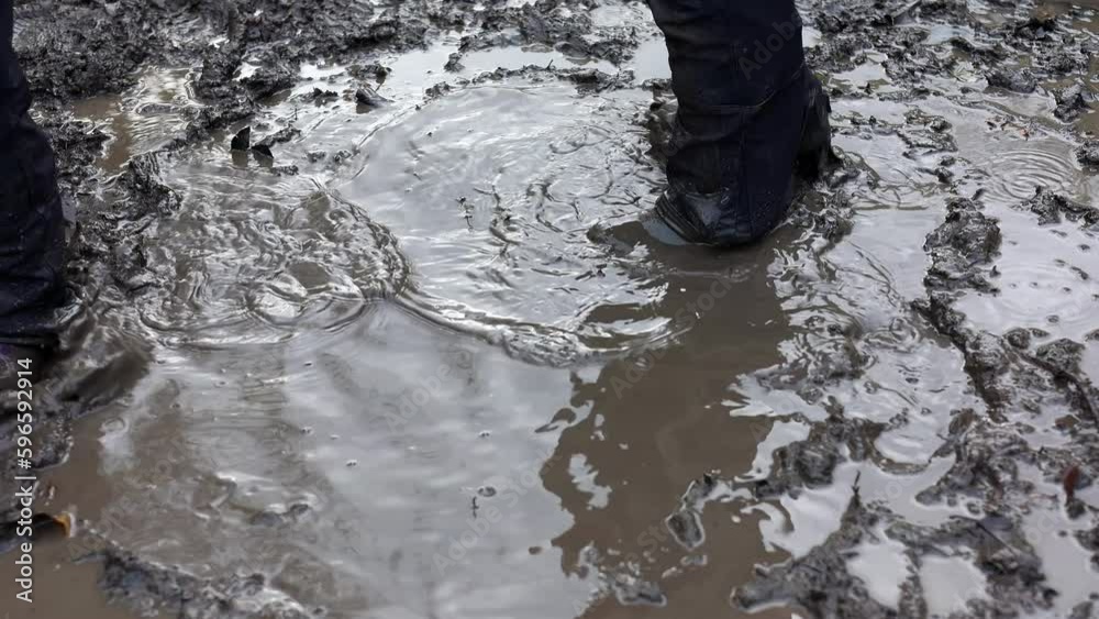 Two young children messing around in a muddy puddle, wearing waterproof ...