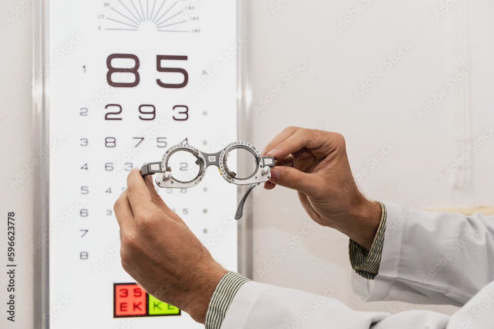 Optometrist holsing eye testing frame with blurred snellen chart ...