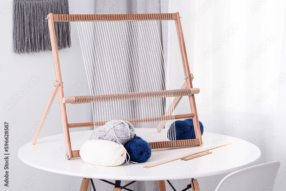 Tools for weaving tapestries. Wooden weaving frame and yarn on a table ...