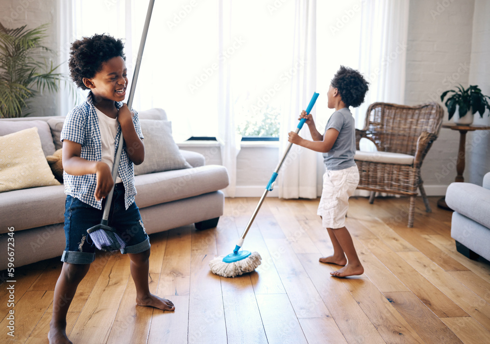 Two mixed race little boys playing with a mop and broom in the lounge ...