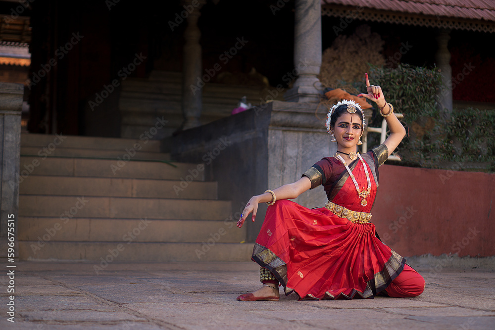 Indian Bharatanatyam dancer performing various steps wearing red saree ...