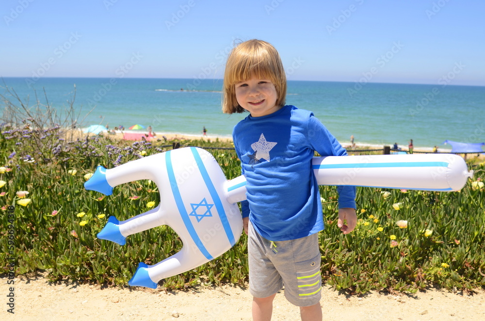 A little boy with an inflatable toy with the Flag of Israel and the ...
