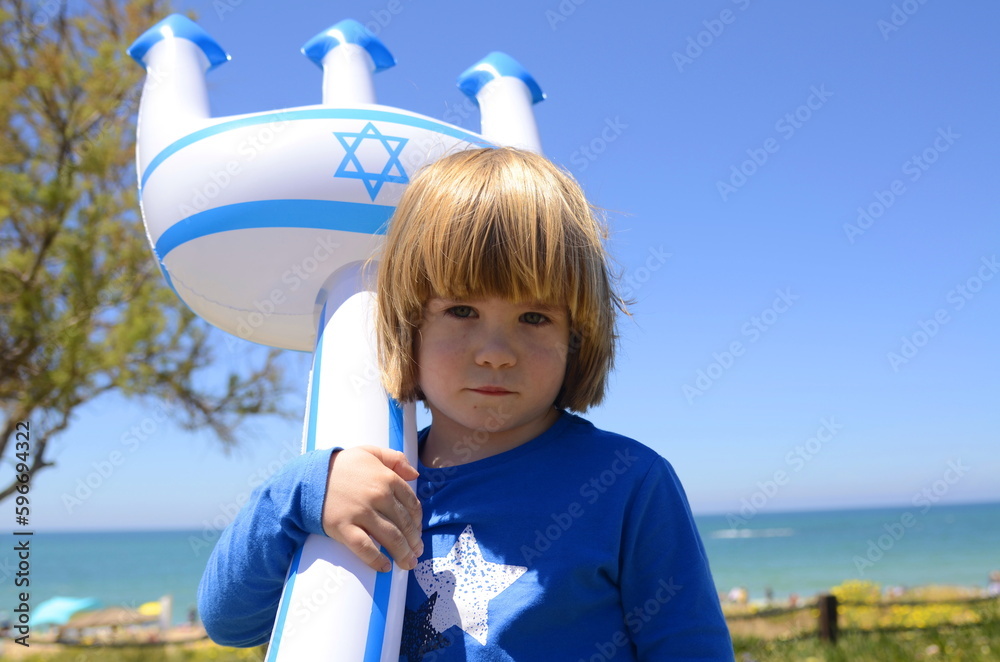 A little boy with an inflatable toy with the Flag of Israel and the ...