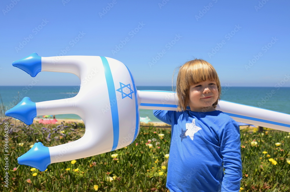 A little boy with an inflatable toy with the Flag of Israel and the ...