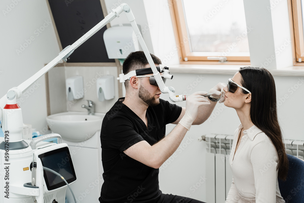 Laser treatment of chronic rhinitis. ENT doctor with laser treats girl ...