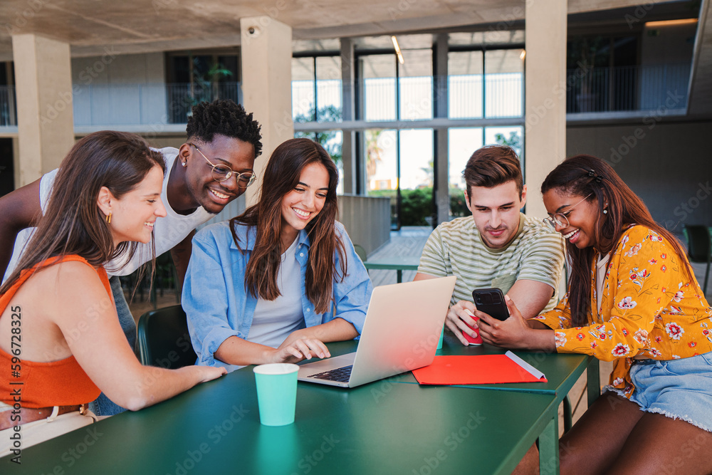 Foto de Group of smiling multiracial international students learning with a laptop at the ...