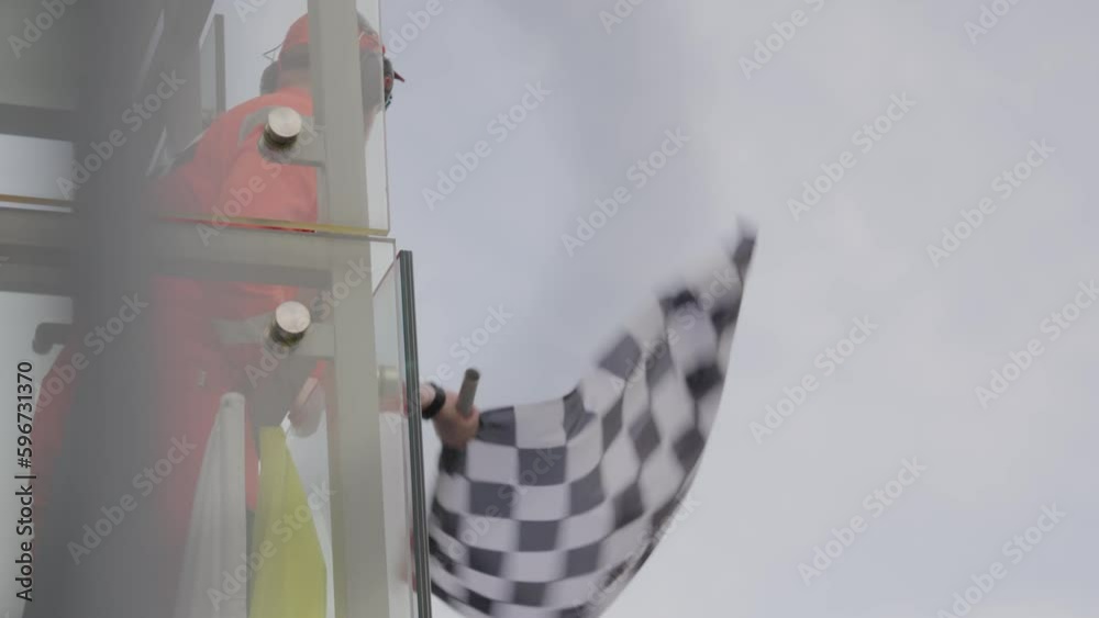 Man holding and waving Checkered race at finish line on a F1 raceway. Victory, achievement ...