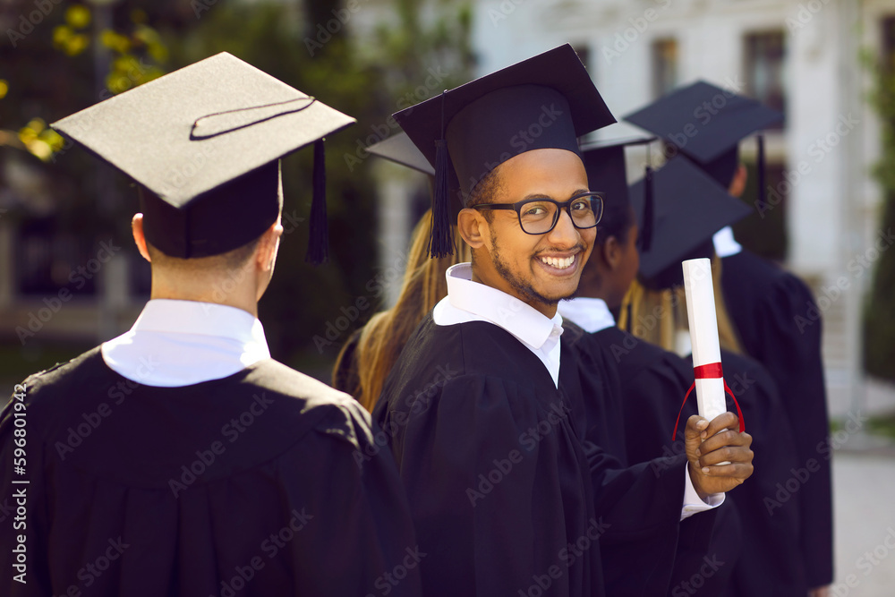 Half turned smiling indian graduate man in glasses in graduation ...